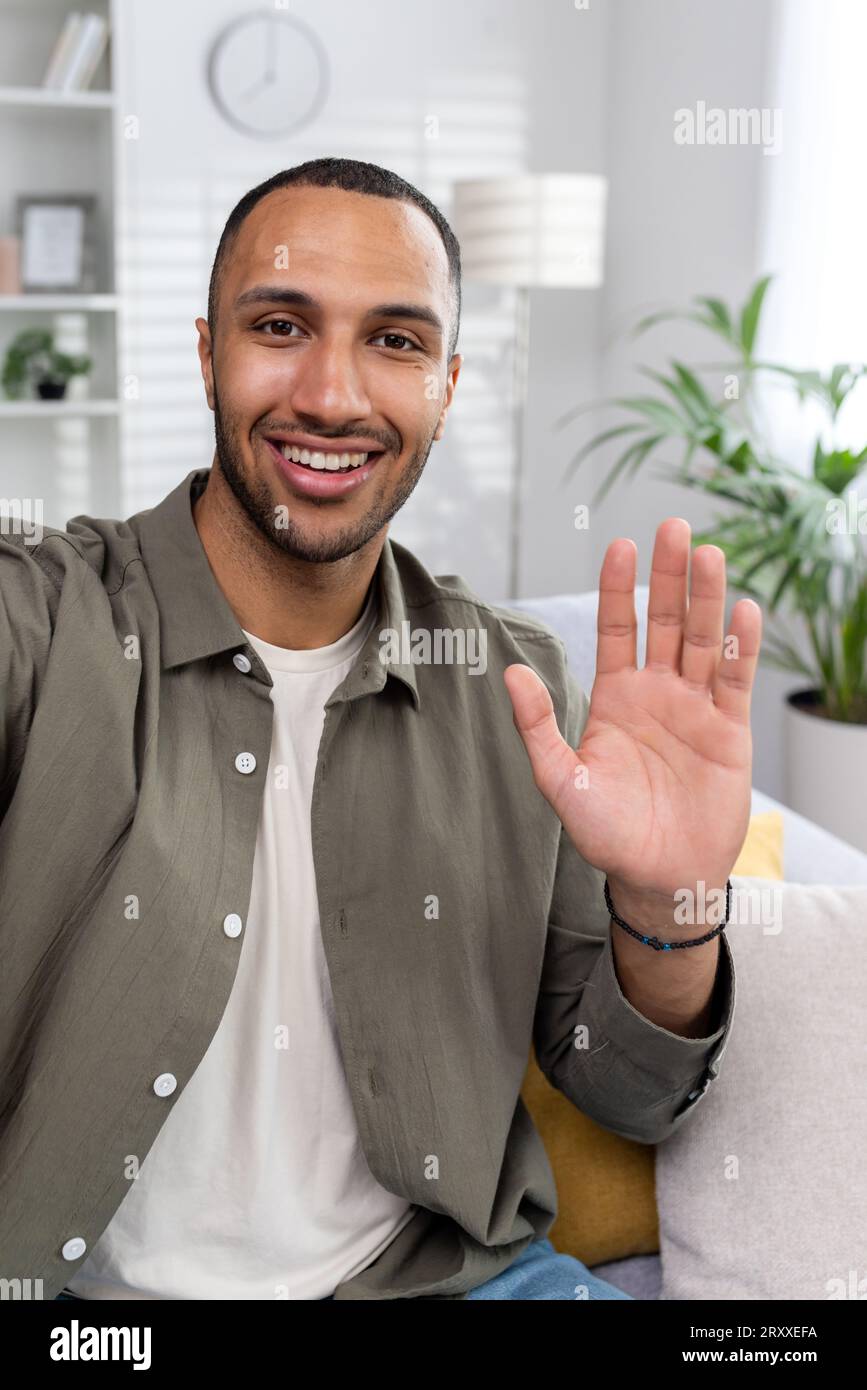 Vertical photo. A young smiling Muslim man is doing an online video ...