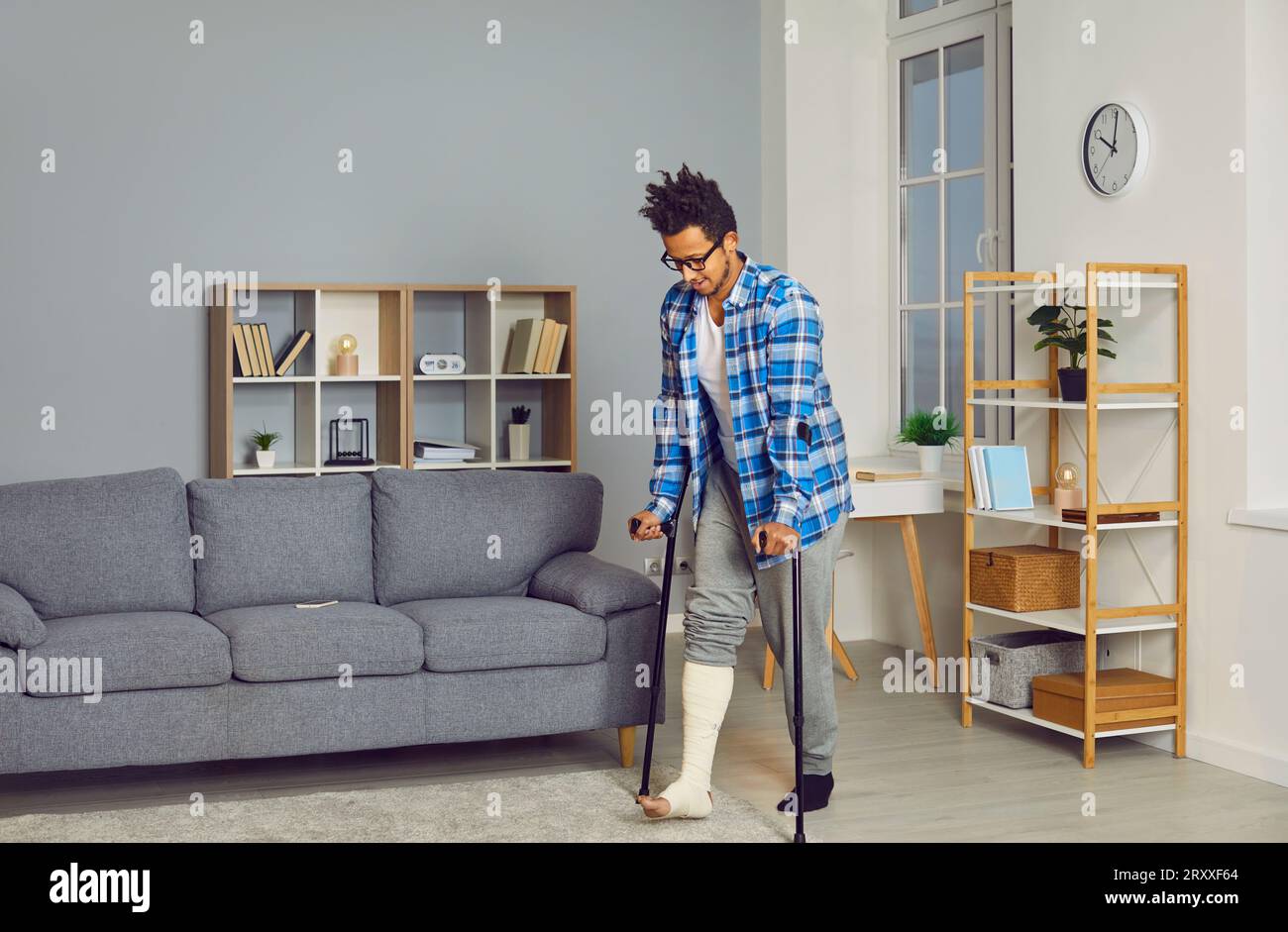 Disabled man using crutches for walking in living room Stock Photo - Alamy