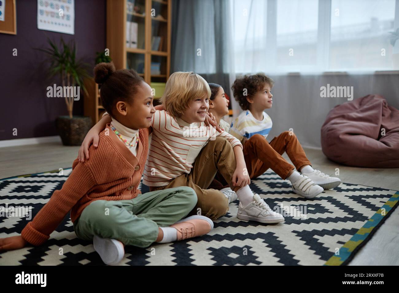 Diverse group of little children sitting on floor in preschool class in ...
