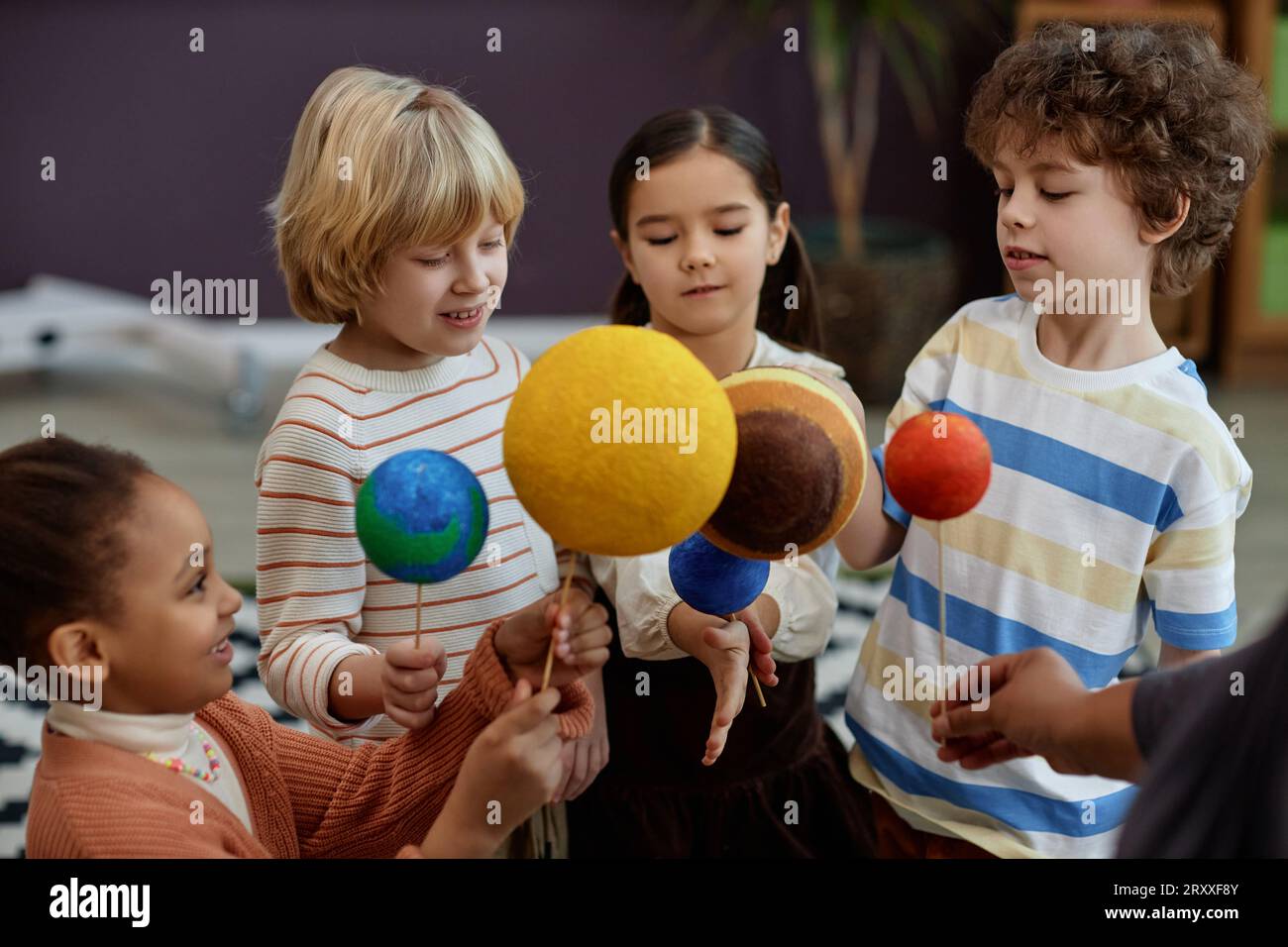 Diverse group of children holding planet models in preschool class and ...
