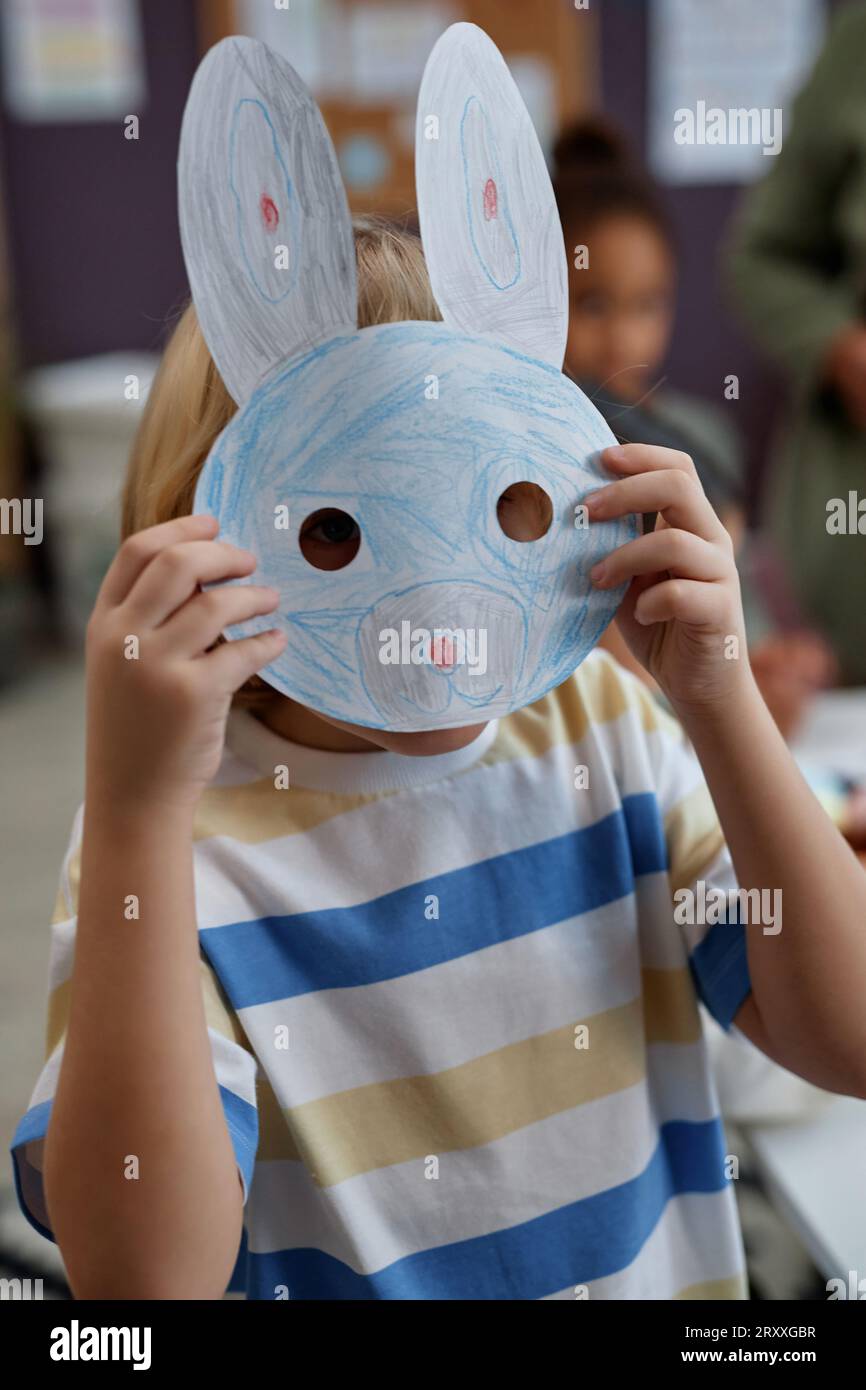 Vertical portrait of cute little boy with handmade Easter Bunny mask in ...