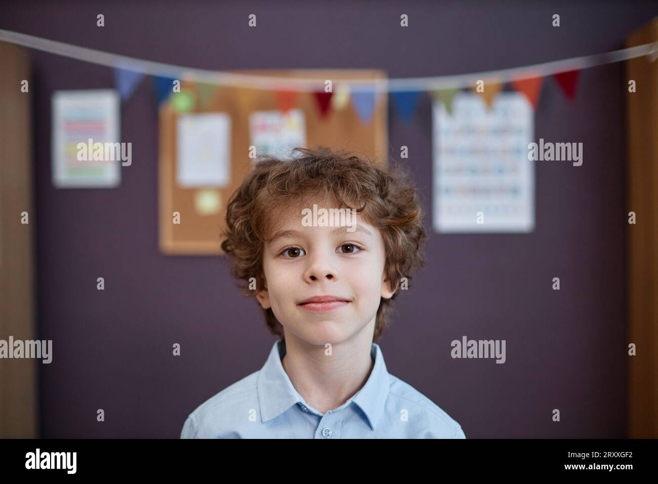 Front view portrait of cute curly haired boy looking at camera in ...