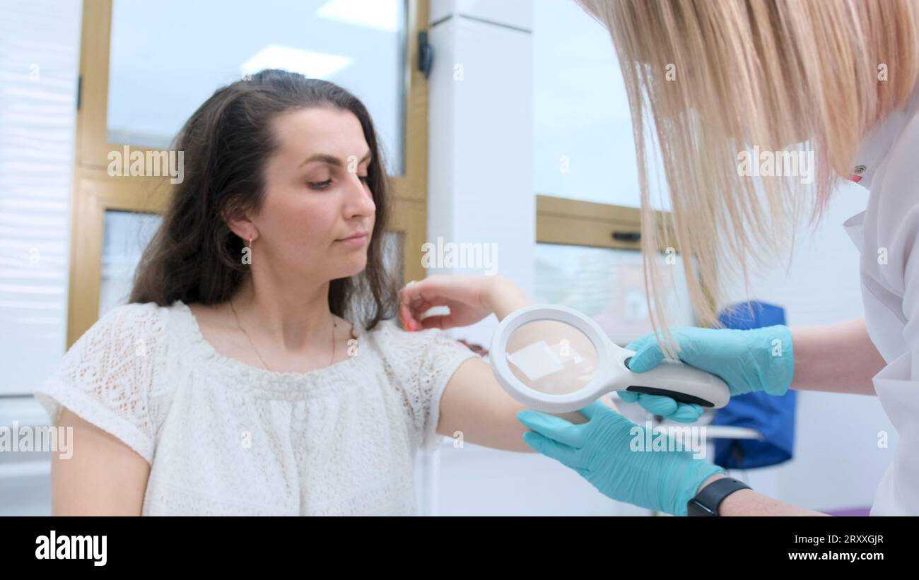a female dermatologist using a medical magnifying glass in the clinic ...