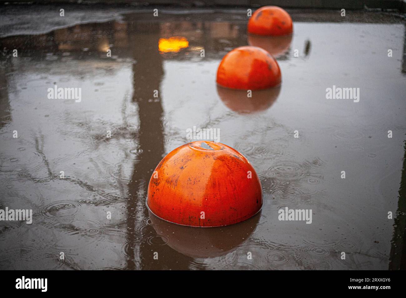 Rain on the road. Parking stoppers. puddle on asphalt Orange sphere in ...