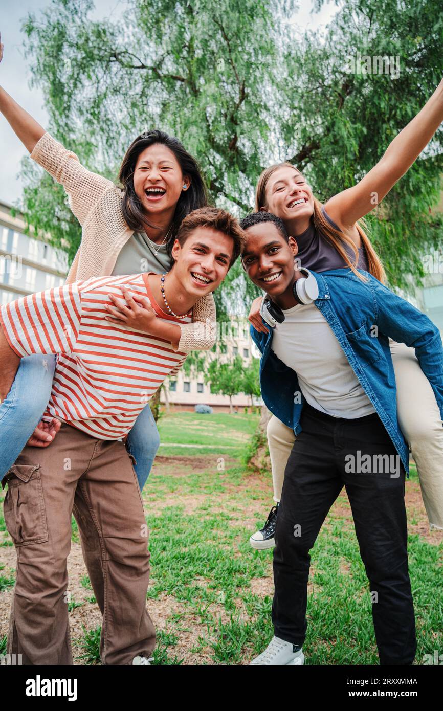 Vertical portrait of multiracial teenage student best friends giving a ...