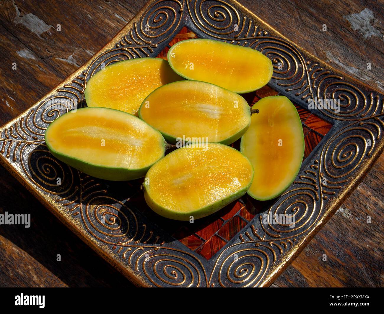 Mangos (Mangifera indica) in decorative fruit bowl, yellow flesh, wild ...
