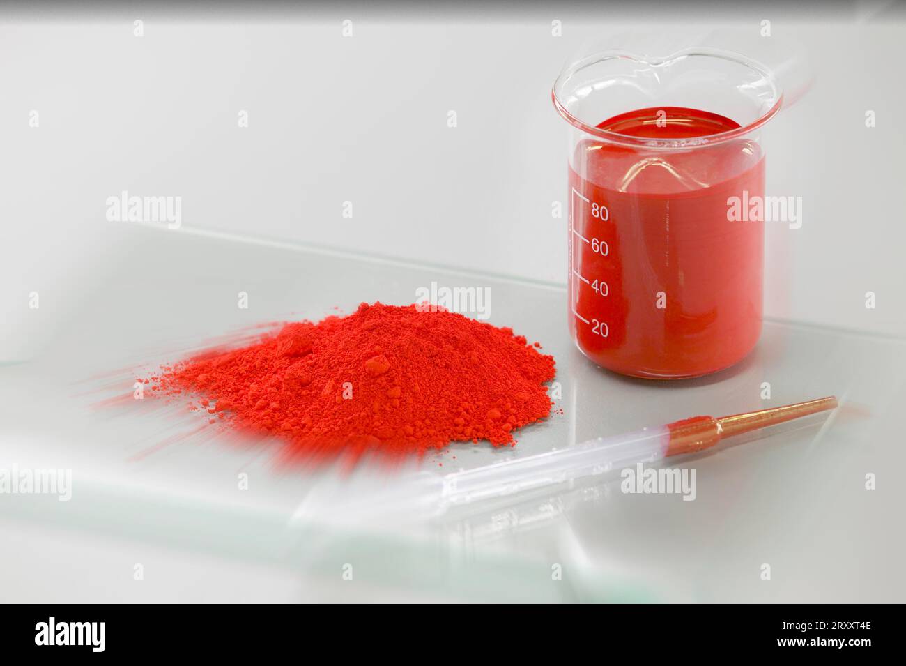 Red dye as powder and dissolved in a laboratory glass with stirring rod ...