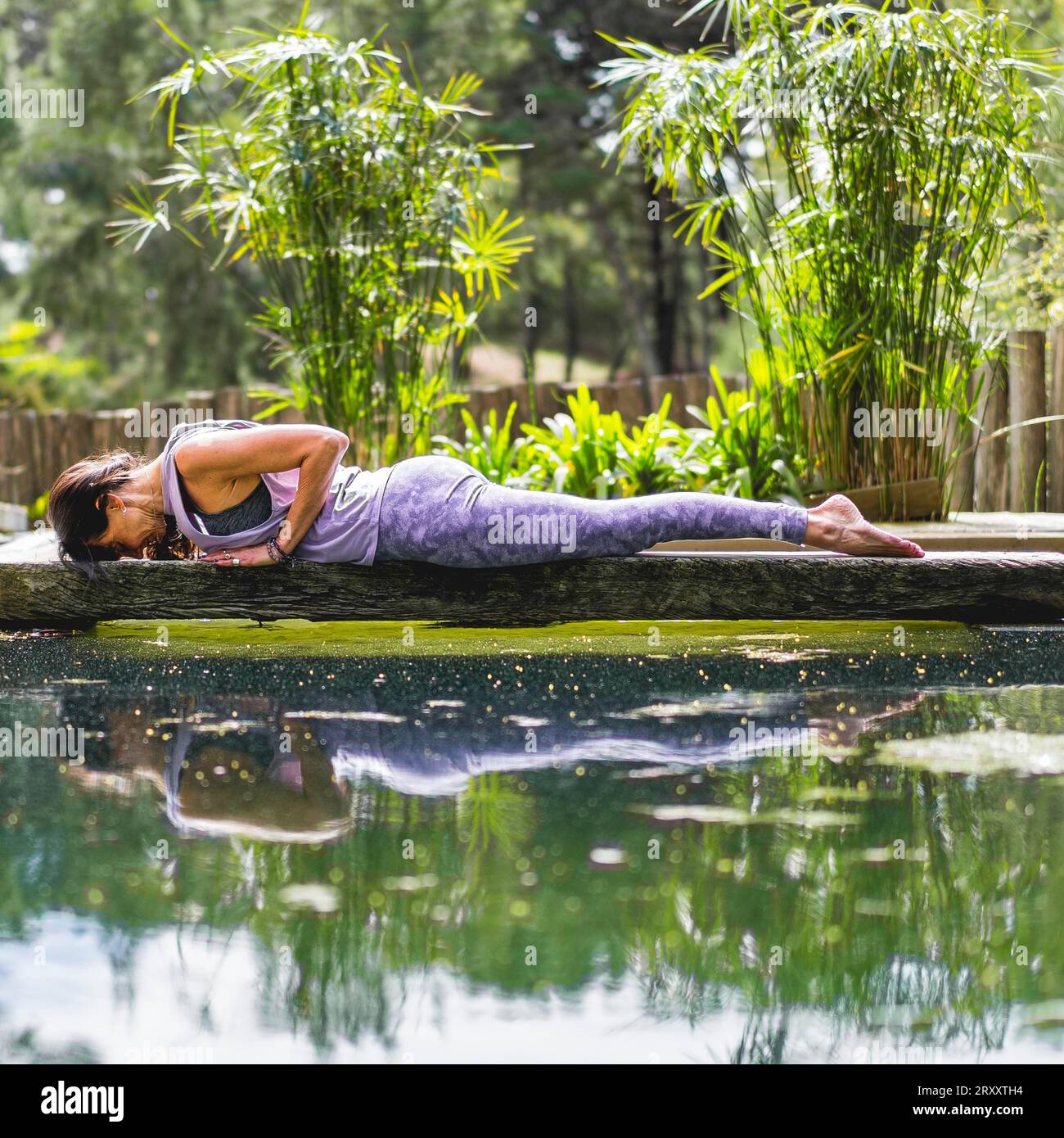 Relaxed mid adult fit woman lying on a tree trunk over the water Stock ...