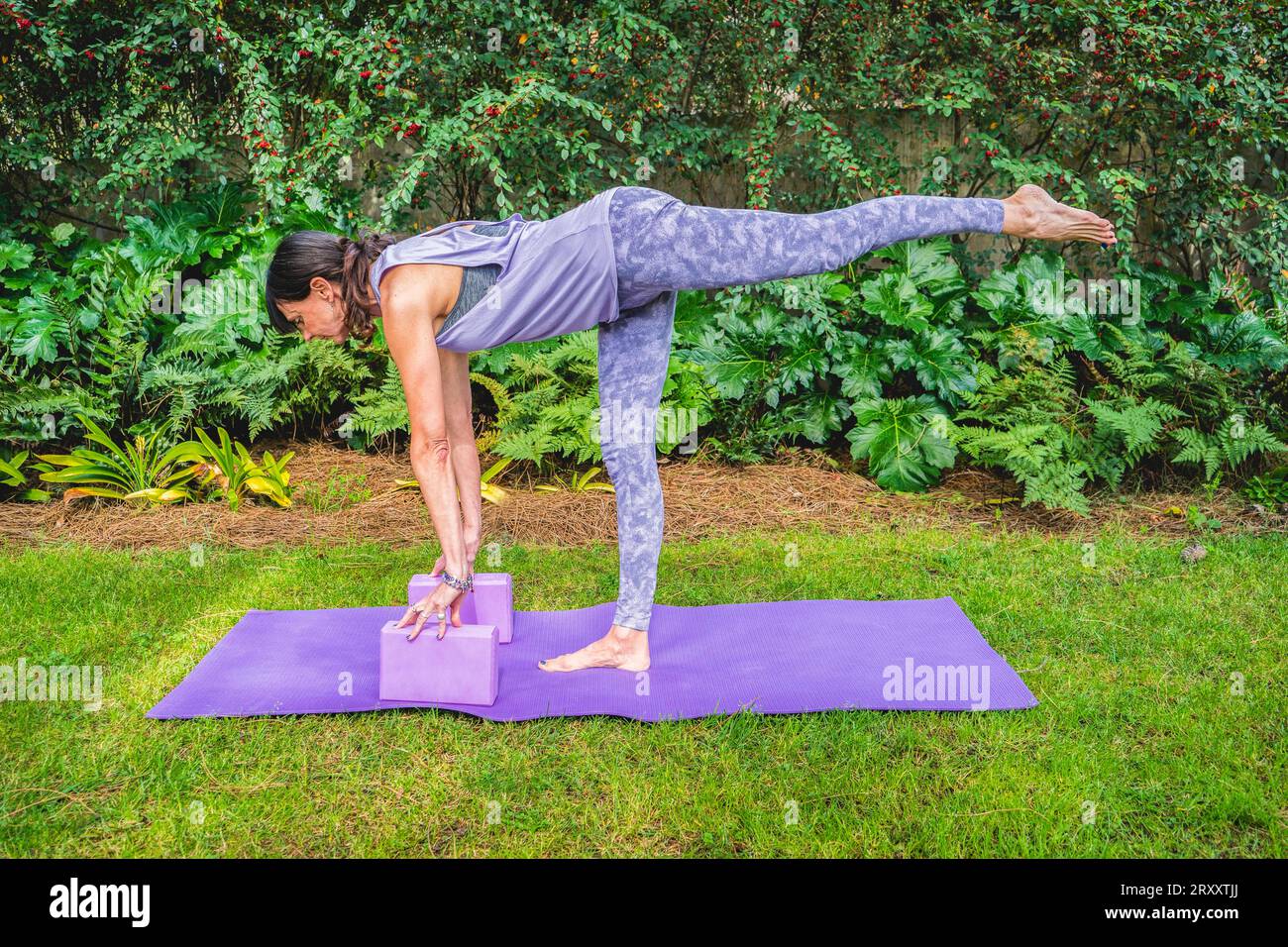 Fit woman in sportswear practices yoga pose using a block outdoors ...