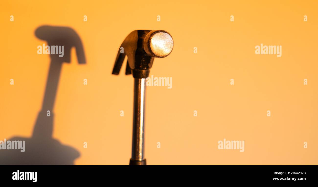 Hammer and its shadow cast on the warm-toned wall, with shallow depth ...