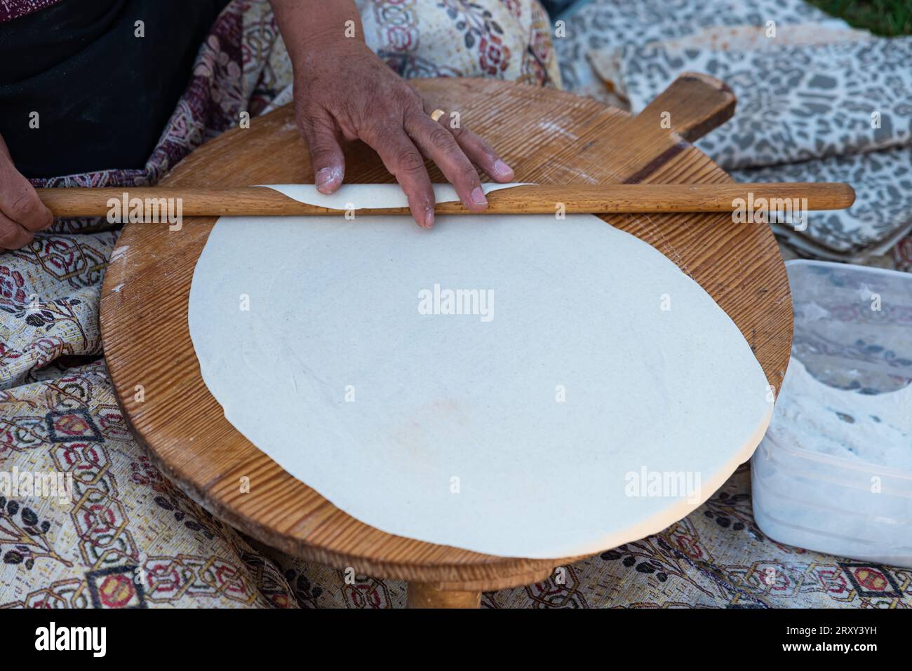 Rolling pin in woman hand rolling dough on traditional mini table ...