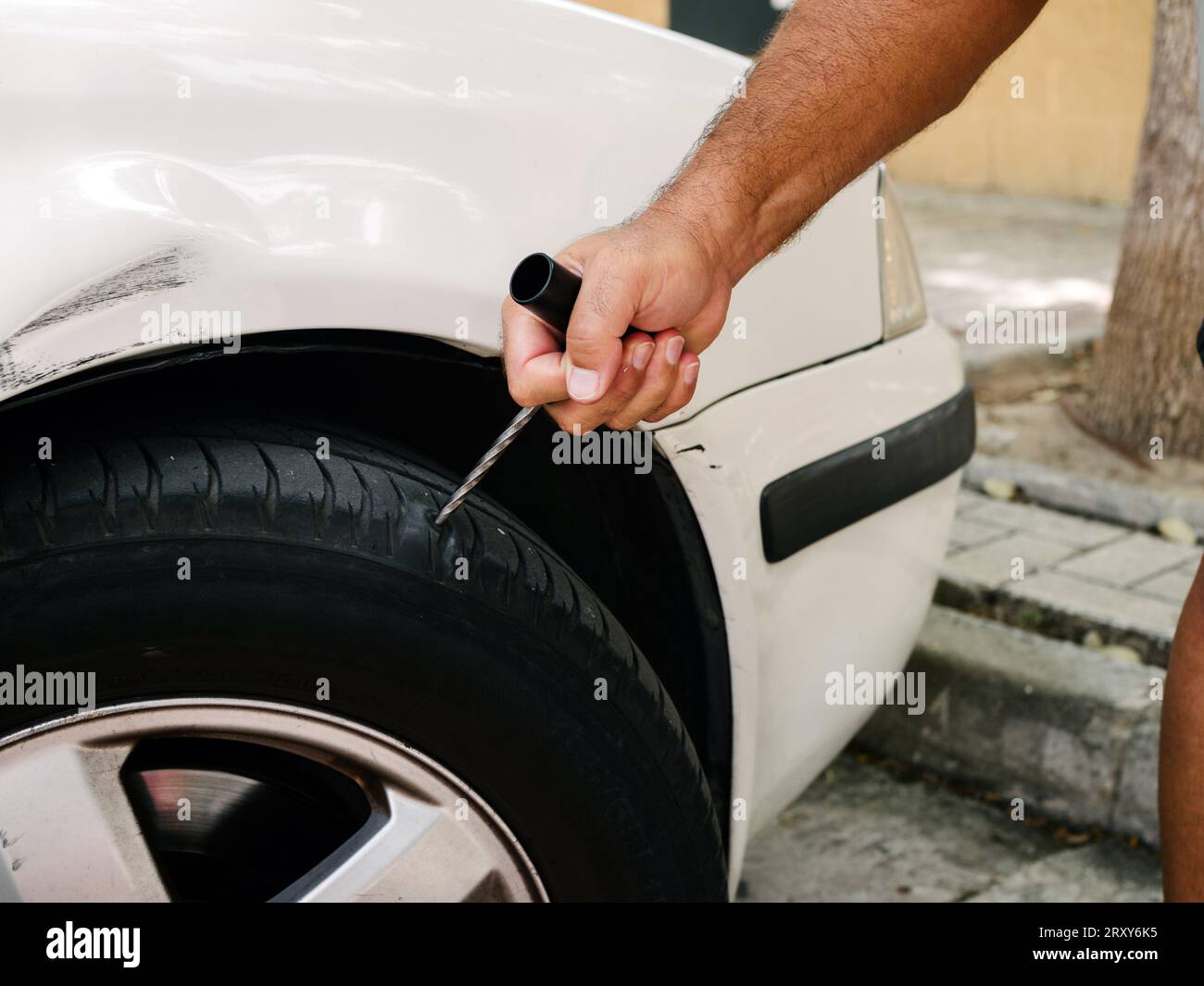 Concept: urban banditry. Hand puncture car tire with punch Stock Photo ...
