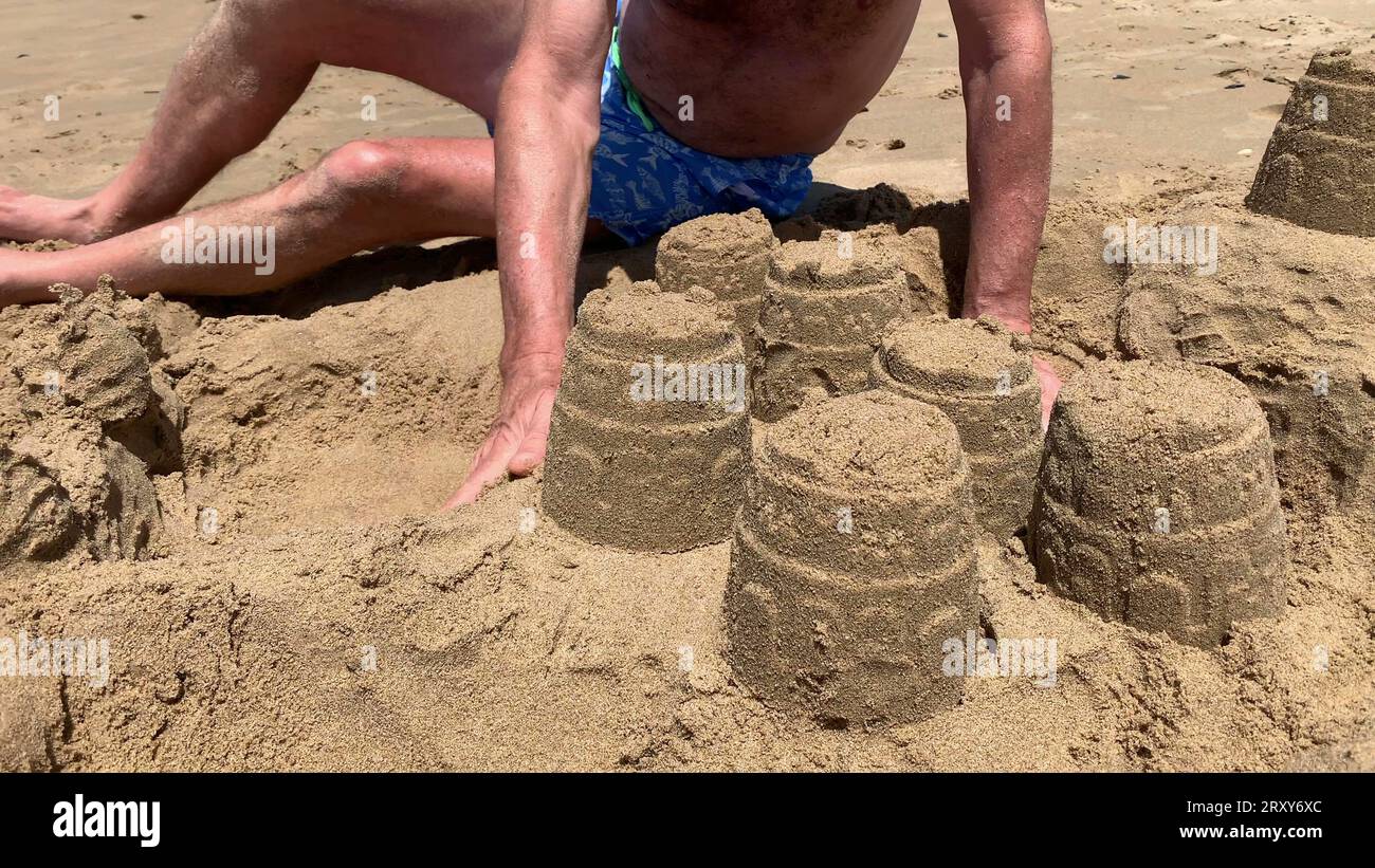 Older man building sandcastle at beach Stock Photo - Alamy