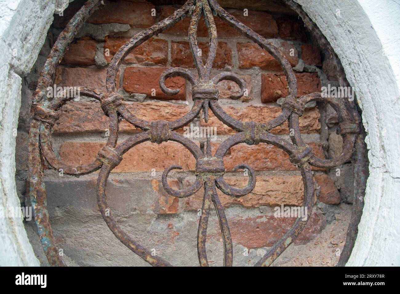 A rusted wrought iron grate over a bricked up round window Stock Photo ...