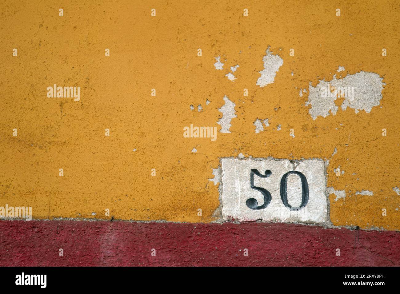 Number 50 on a brightly p[ainted wall, shot close up in landscape ...