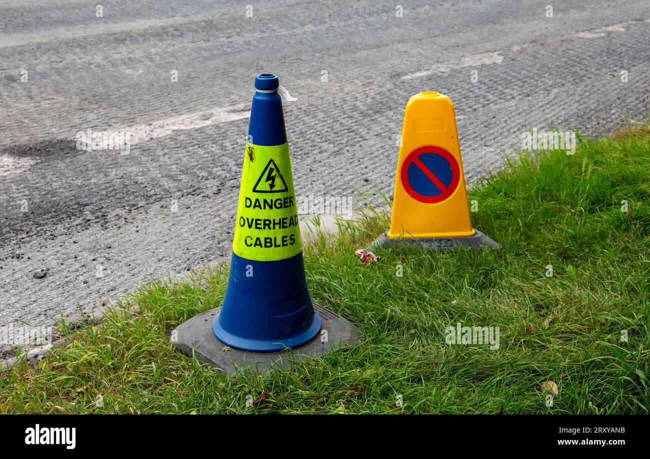 Blue and yellow traffic cones with warning signs placed on roadside ...