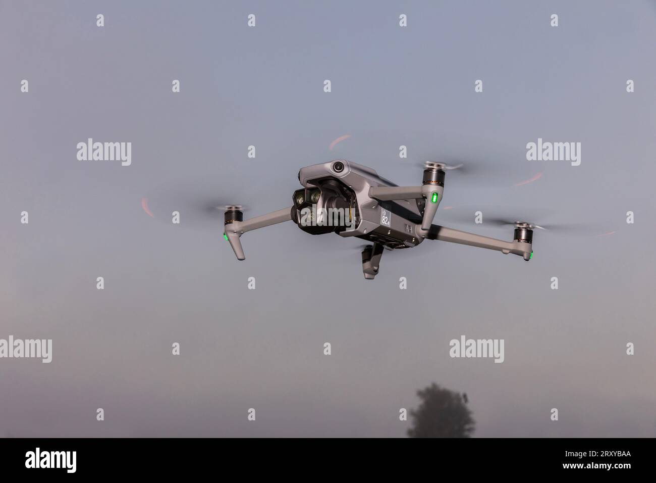 A small foldable drone in flight mode with the spot lights on.. A gray ...