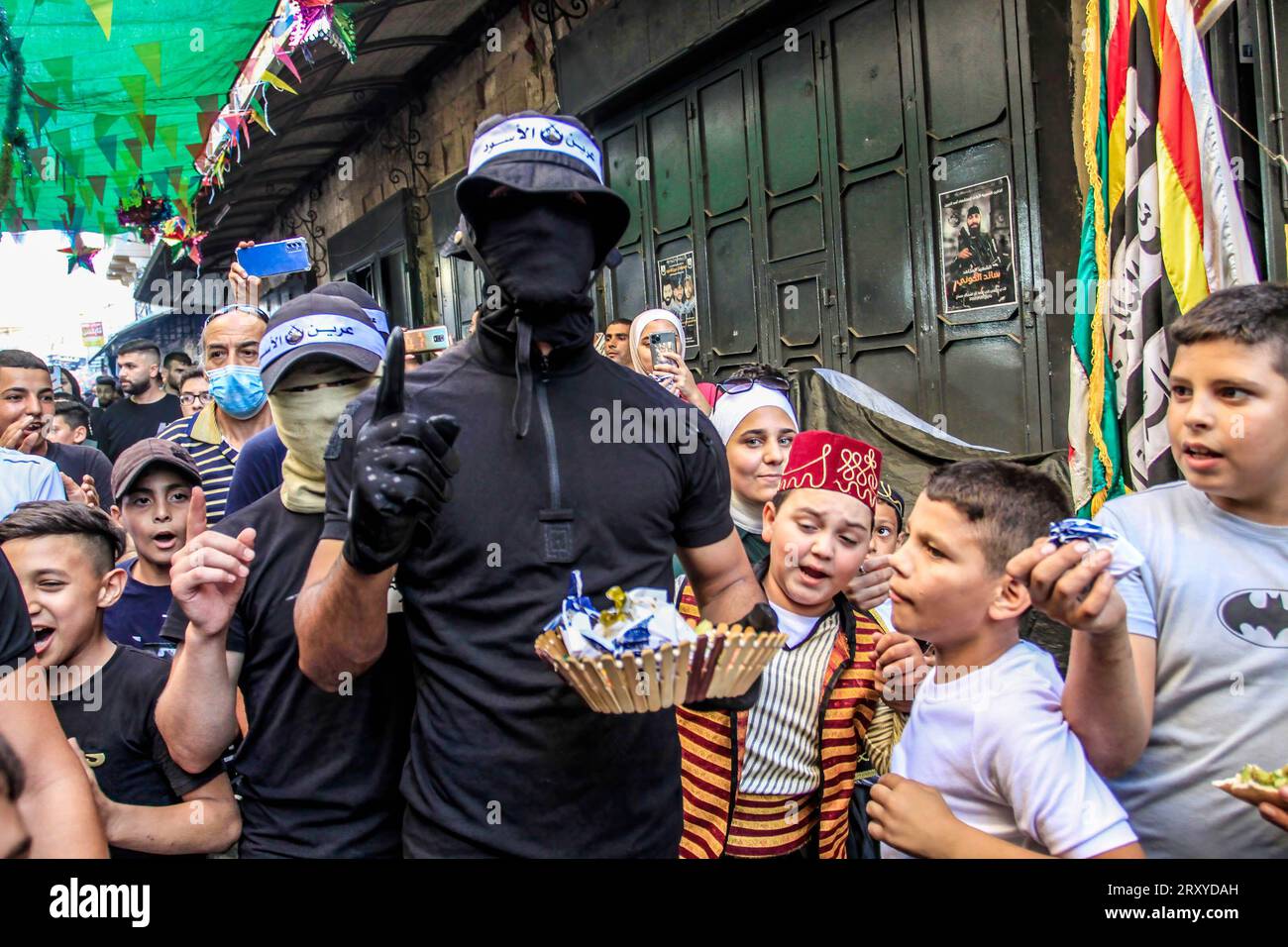Palestinian members of the Lions' Den group distribute sweets to people ...