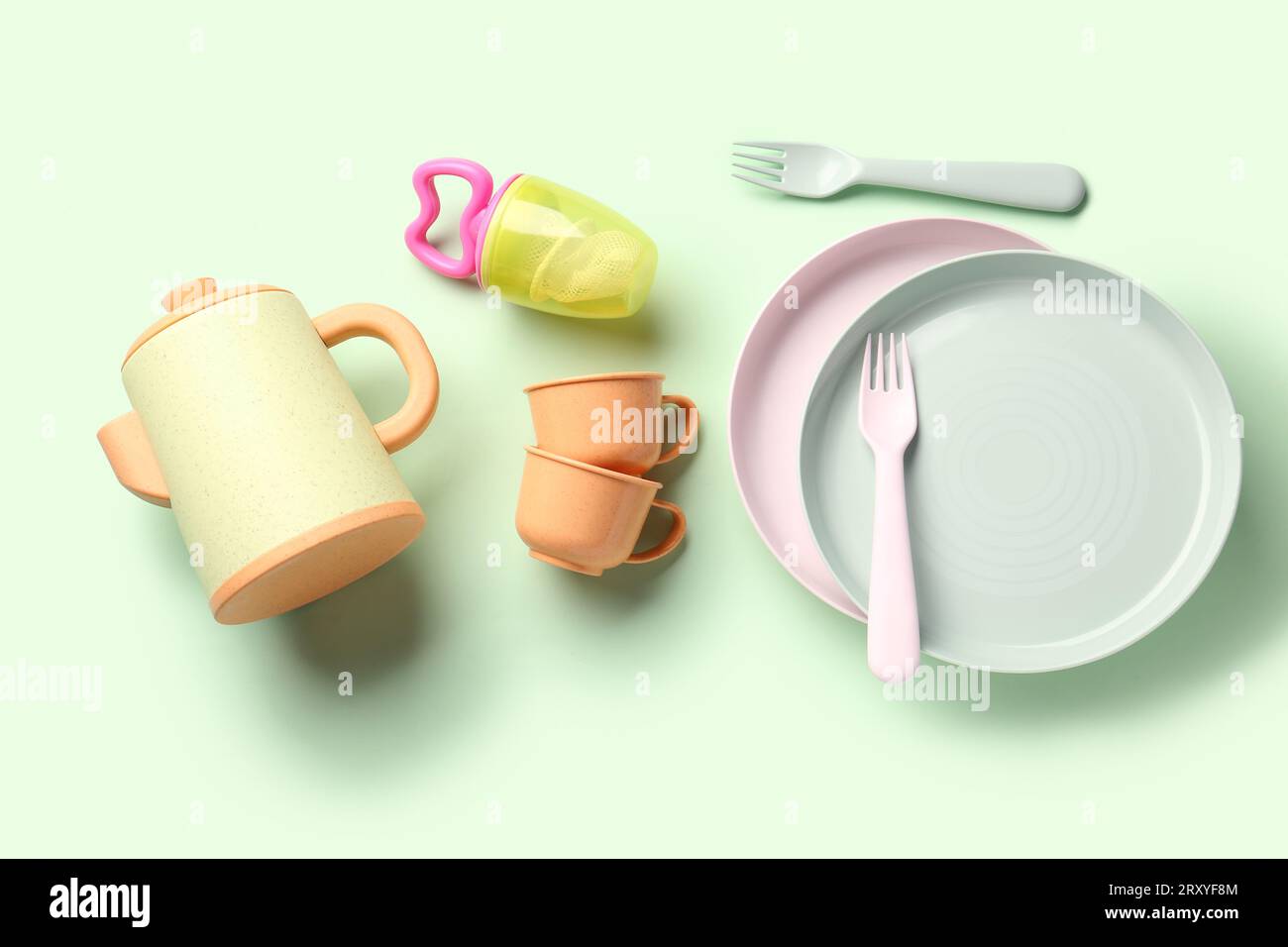 Different eating utensils for baby on pale green background Stock Photo ...