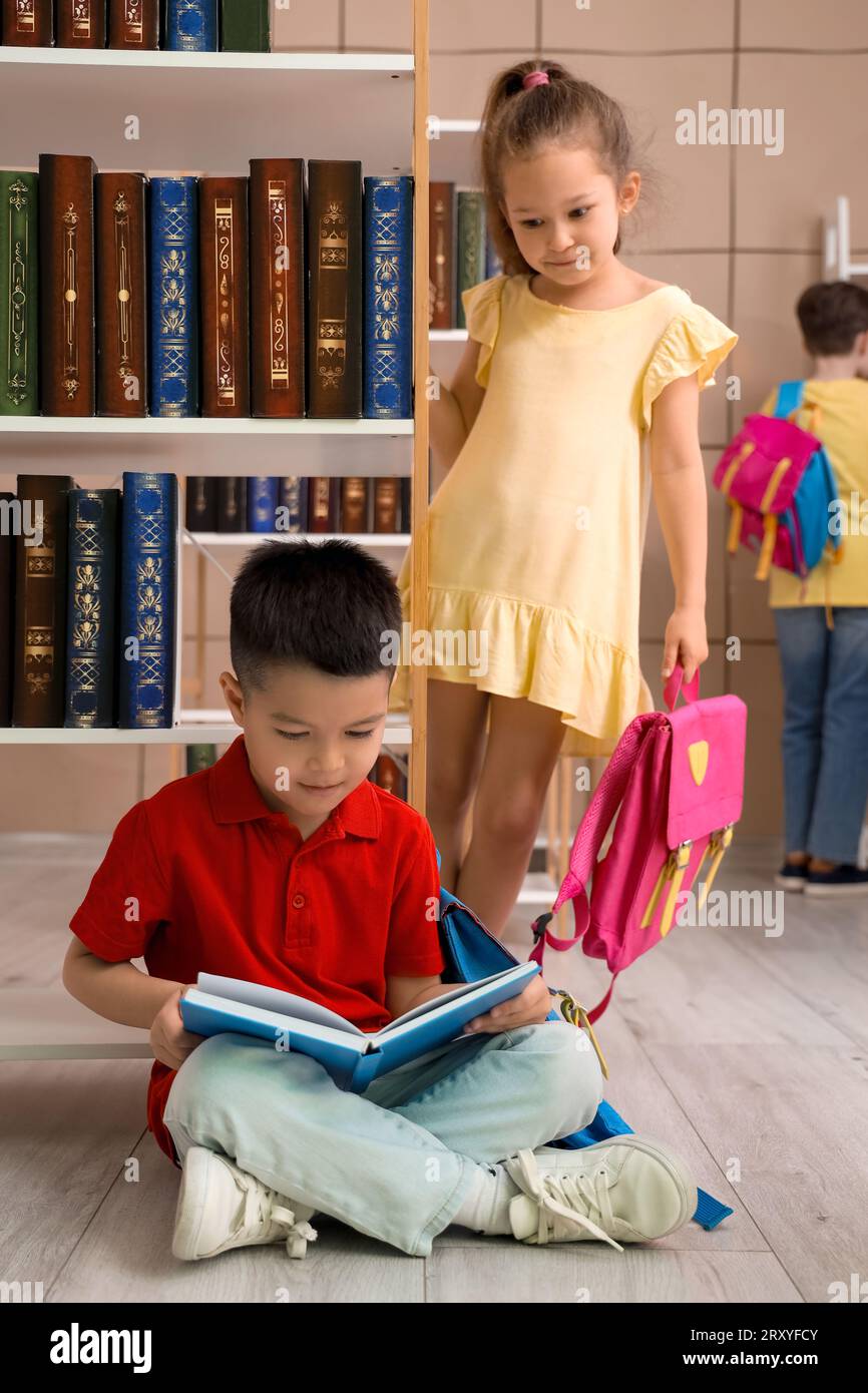 Cute little boy reading book in library Stock Photo - Alamy