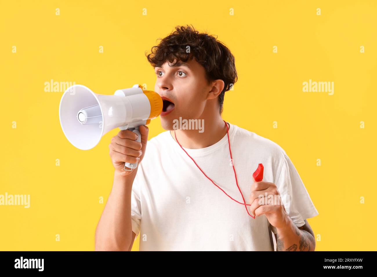 Male lifeguard with whistle shouting into megaphone on yellow ...