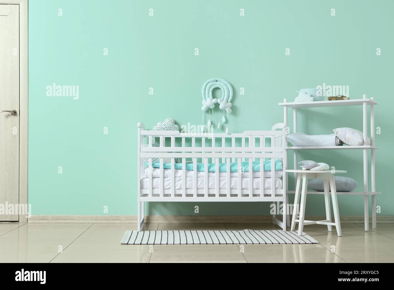 Interior of children's room with crib near turquoise wall Stock Photo ...