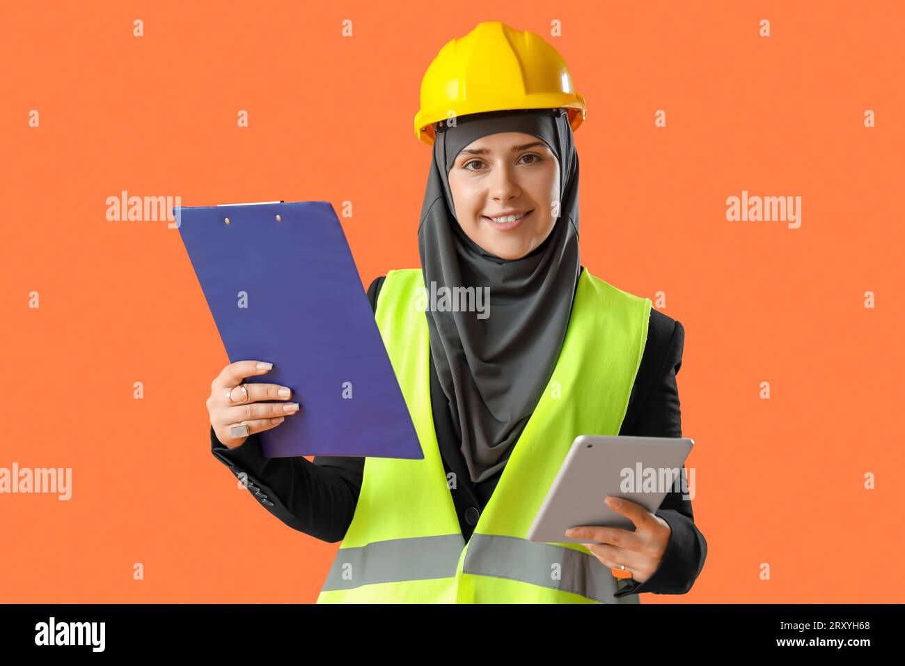 Female Muslim construction worker with clipboard and tablet computer on ...