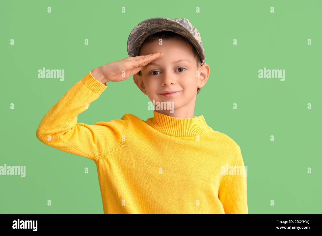 Little boy in military cap saluting on green background. Veterans Day ...