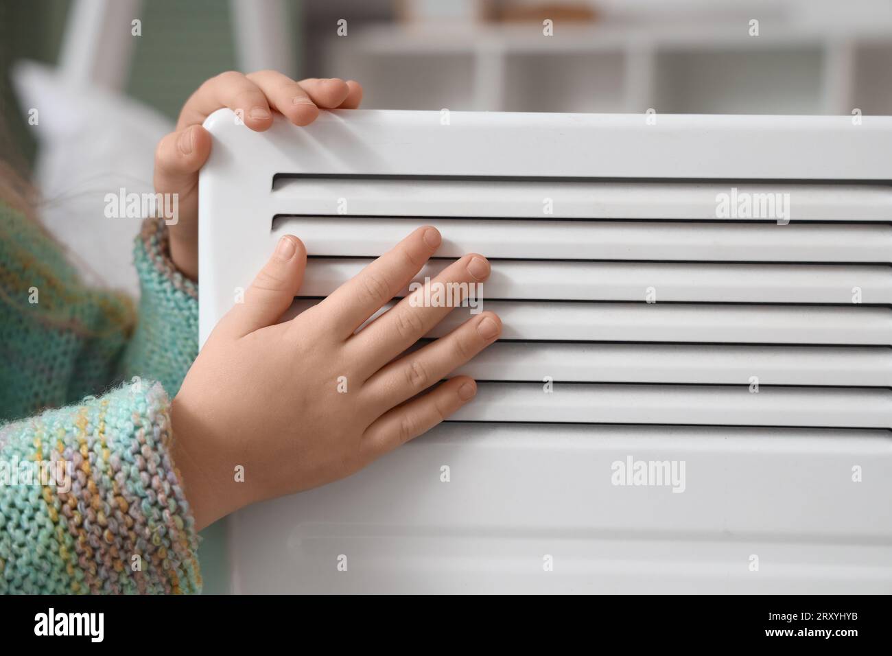 Cute little girl warming hands near radiator at home, closeup Stock ...