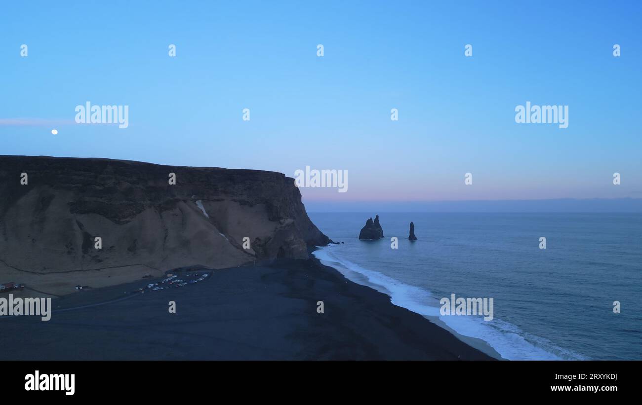 Drone shot of black sand beach with rocks and massive hills in iceland ...