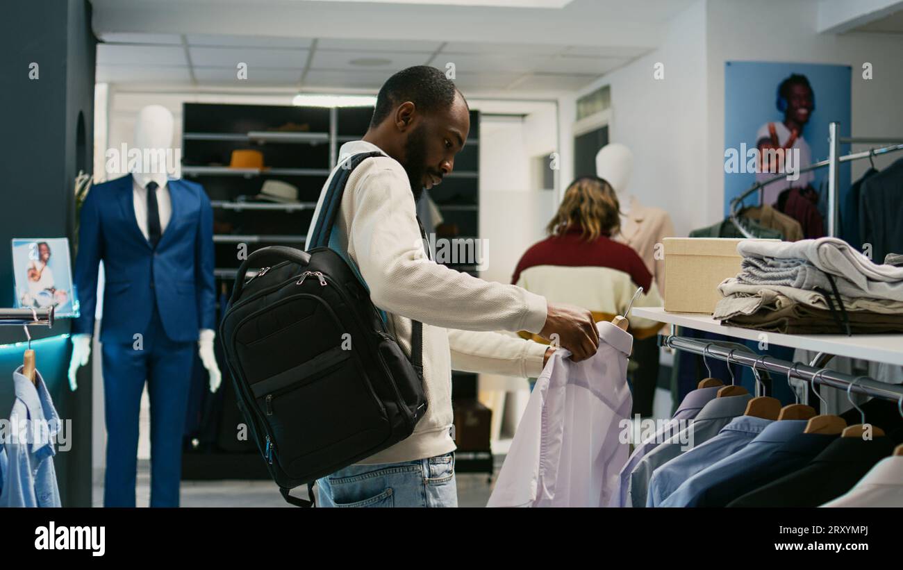 Male shopper buying new shirts for formal wear at mall, looking at new ...