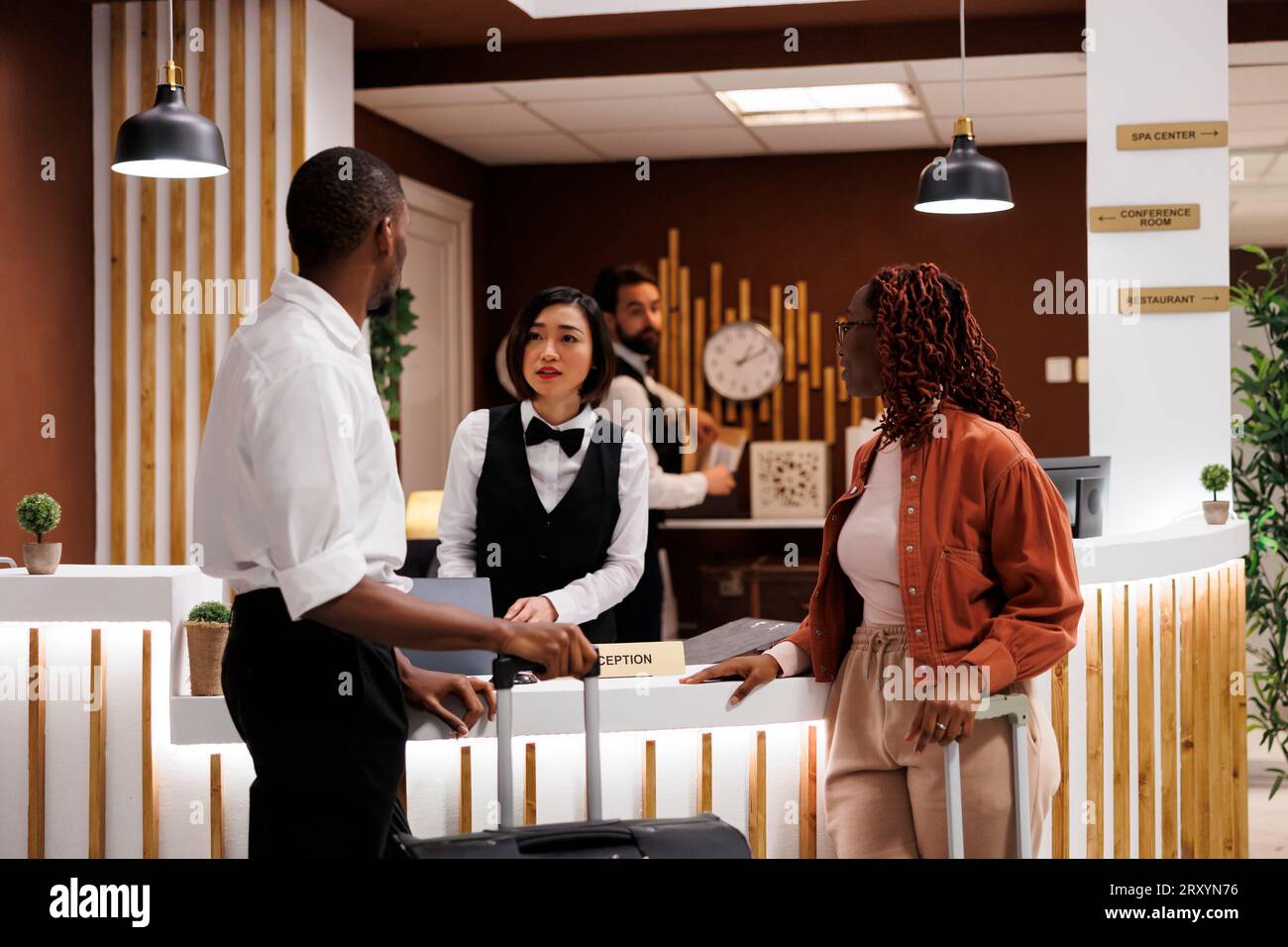 Hotel employee registering people at front desk, using computer to ...