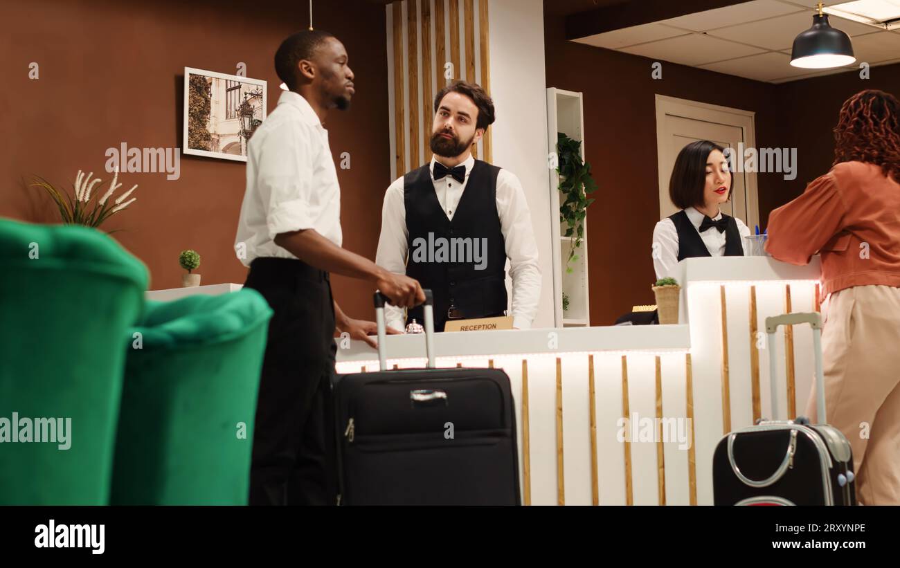 Happy smiling concierge staff team helping tourists with room ...