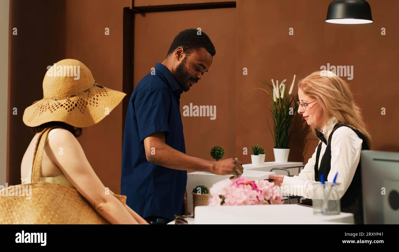 Hotel guests registering at reception, signing electronic check in ...