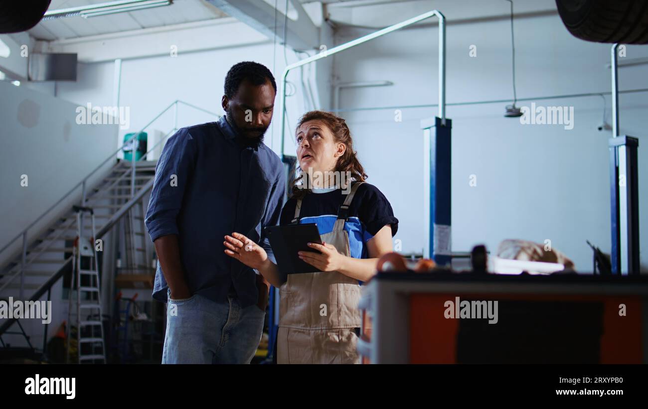 Mechanic in auto repair shop showing customer what needs to be changed ...