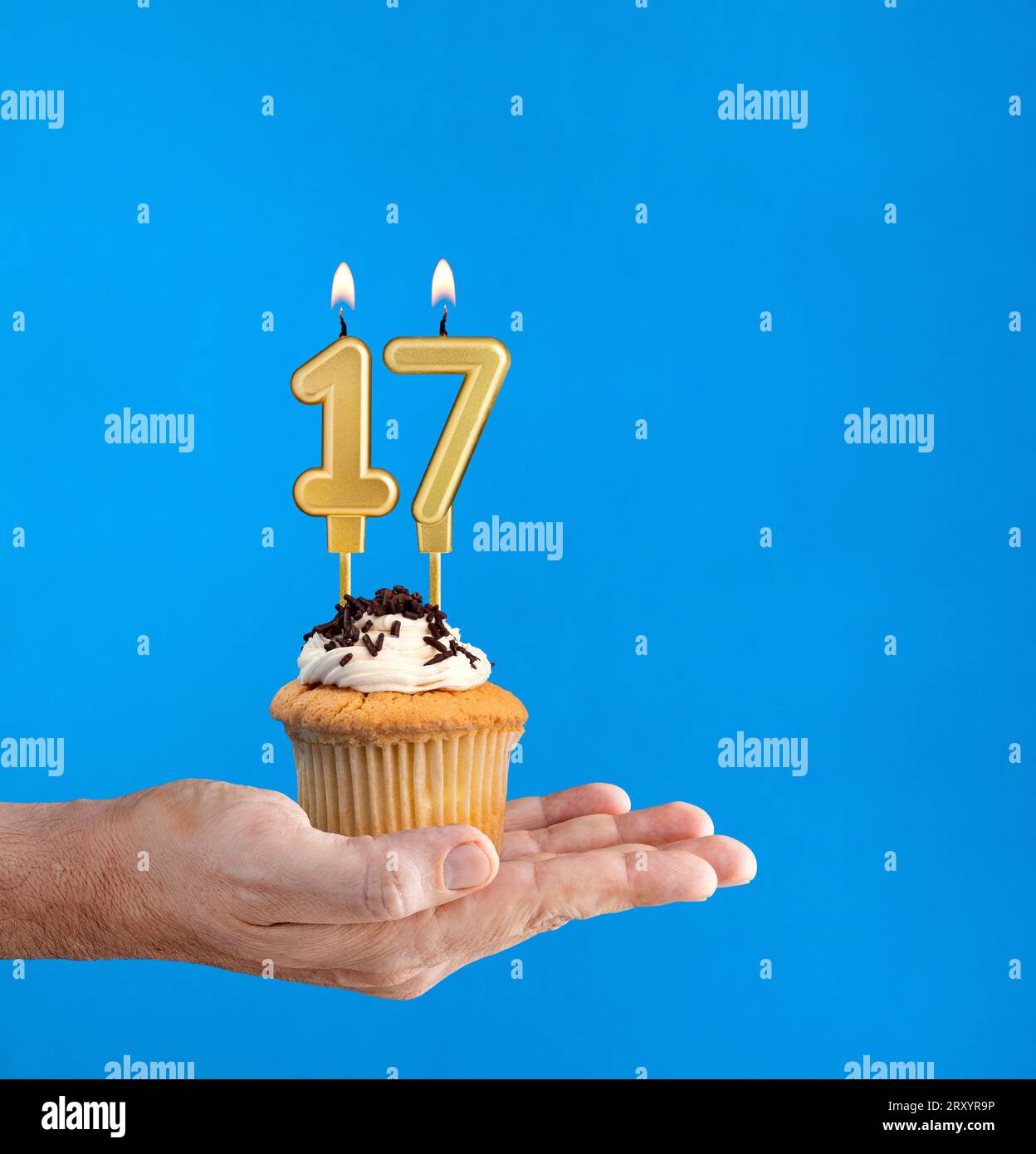 Hand delivering birthday cupcake - Candle number 17 on blue background ...