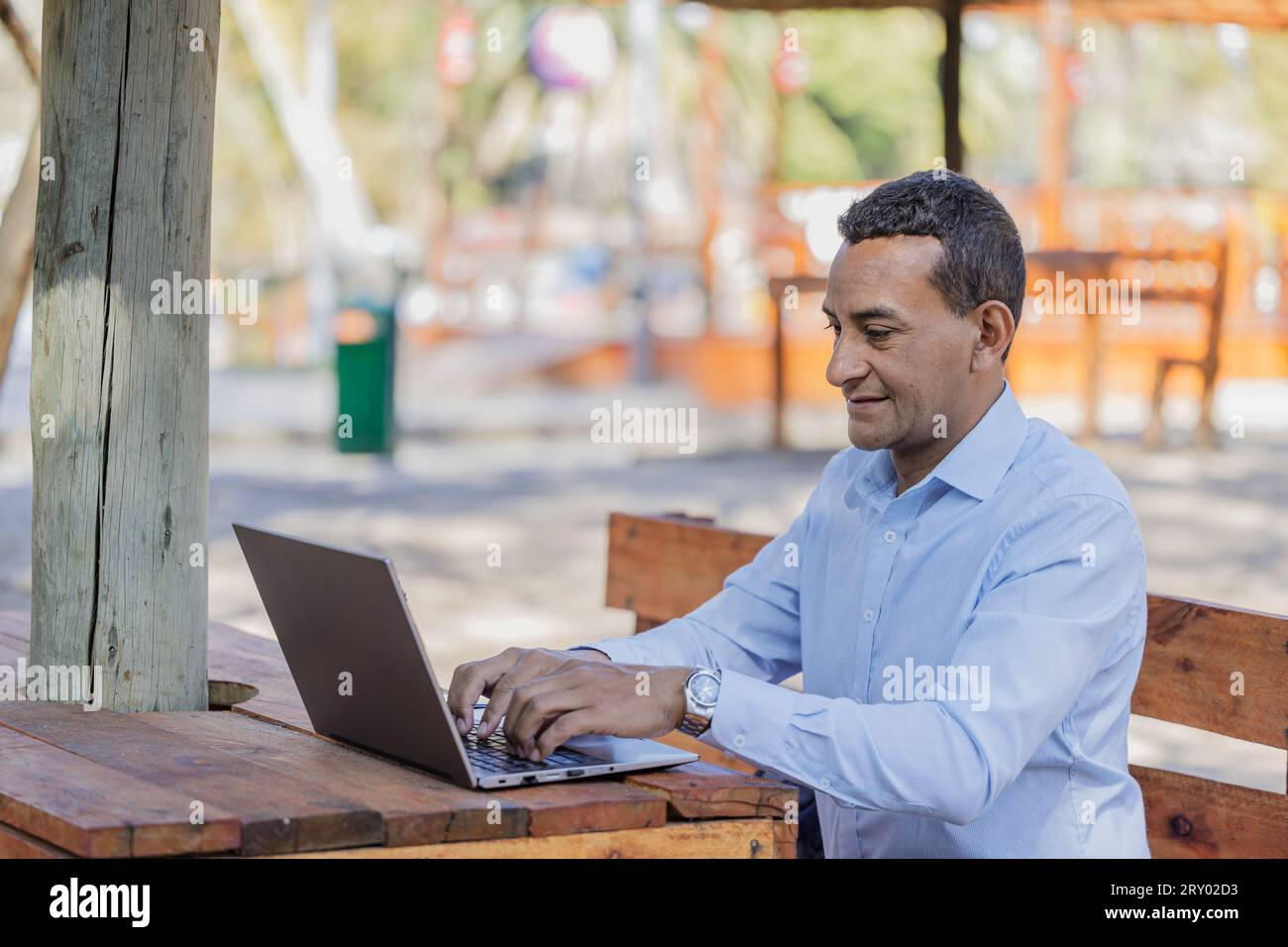 Young Latino man using a laptop outdoors Stock Photo - Alamy