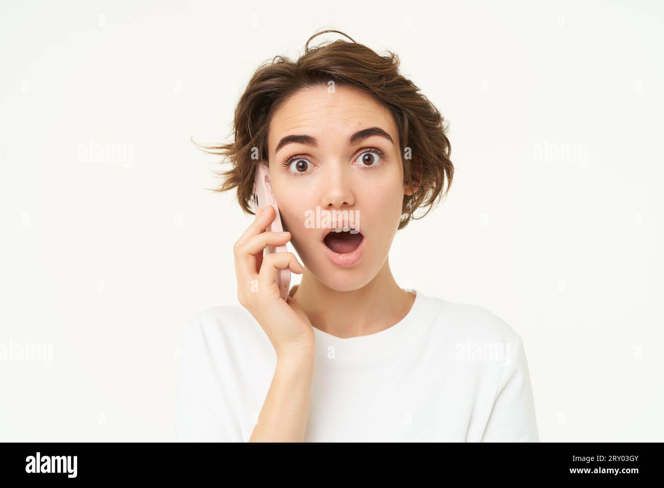 Portrait of woman with surprised face, answers phone call and looks ...