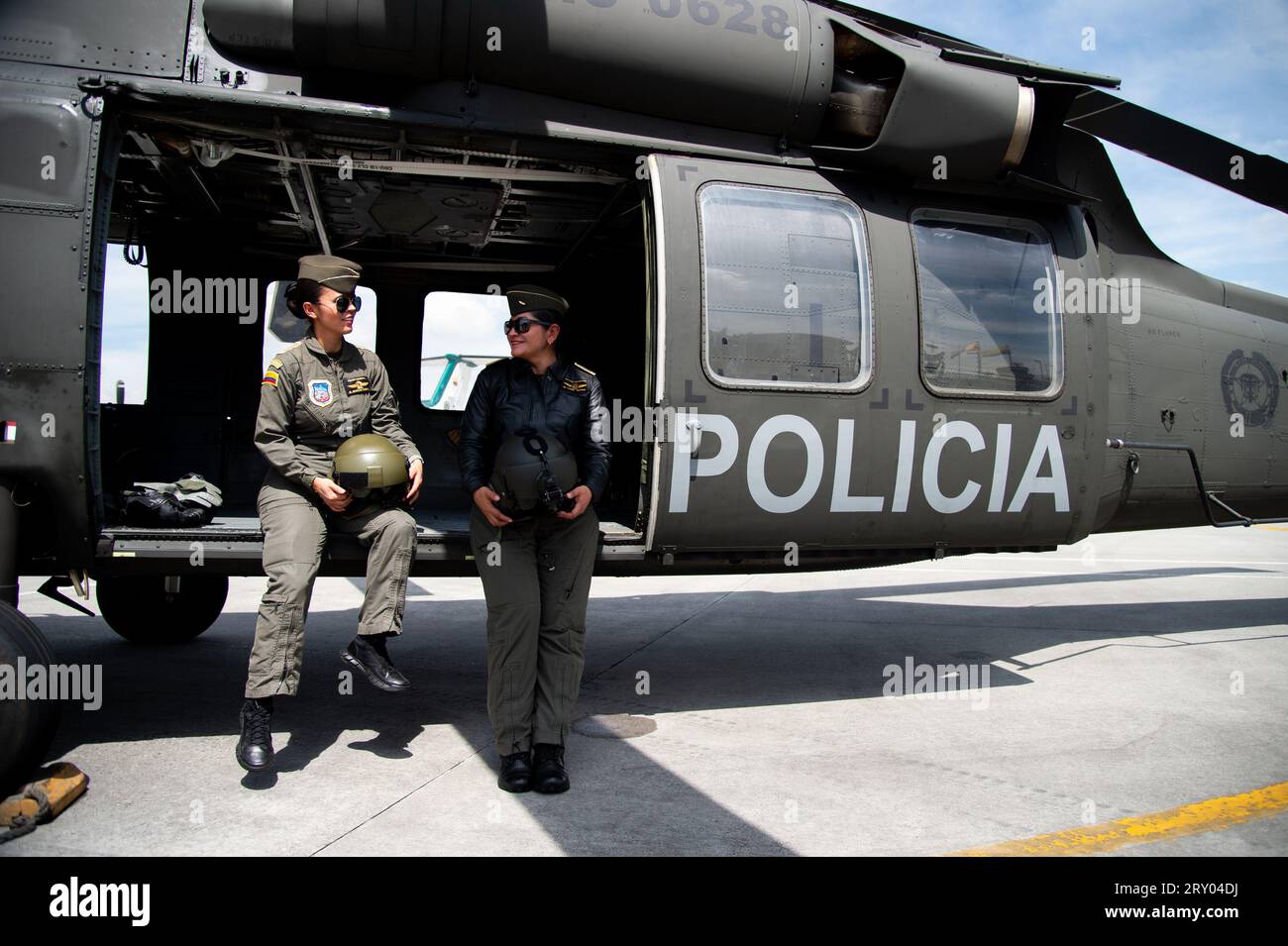 Two Colombian police helicopter polots sit on the door of a UH60 Black ...