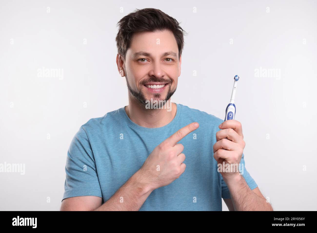 Happy man holding plastic toothbrush on white background. Mouth hygiene ...