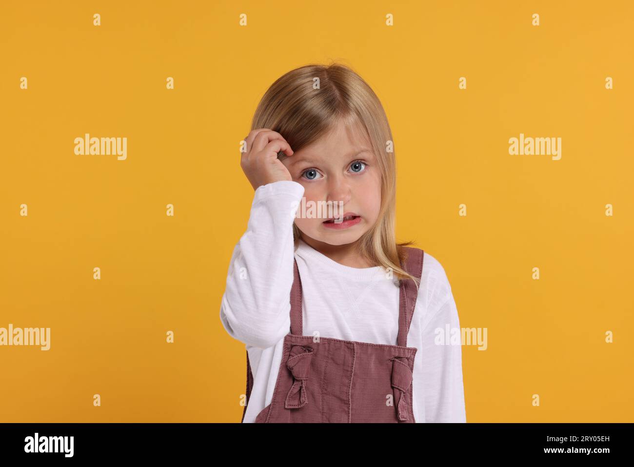 Portrait of embarrassed little girl on orange background Stock Photo ...