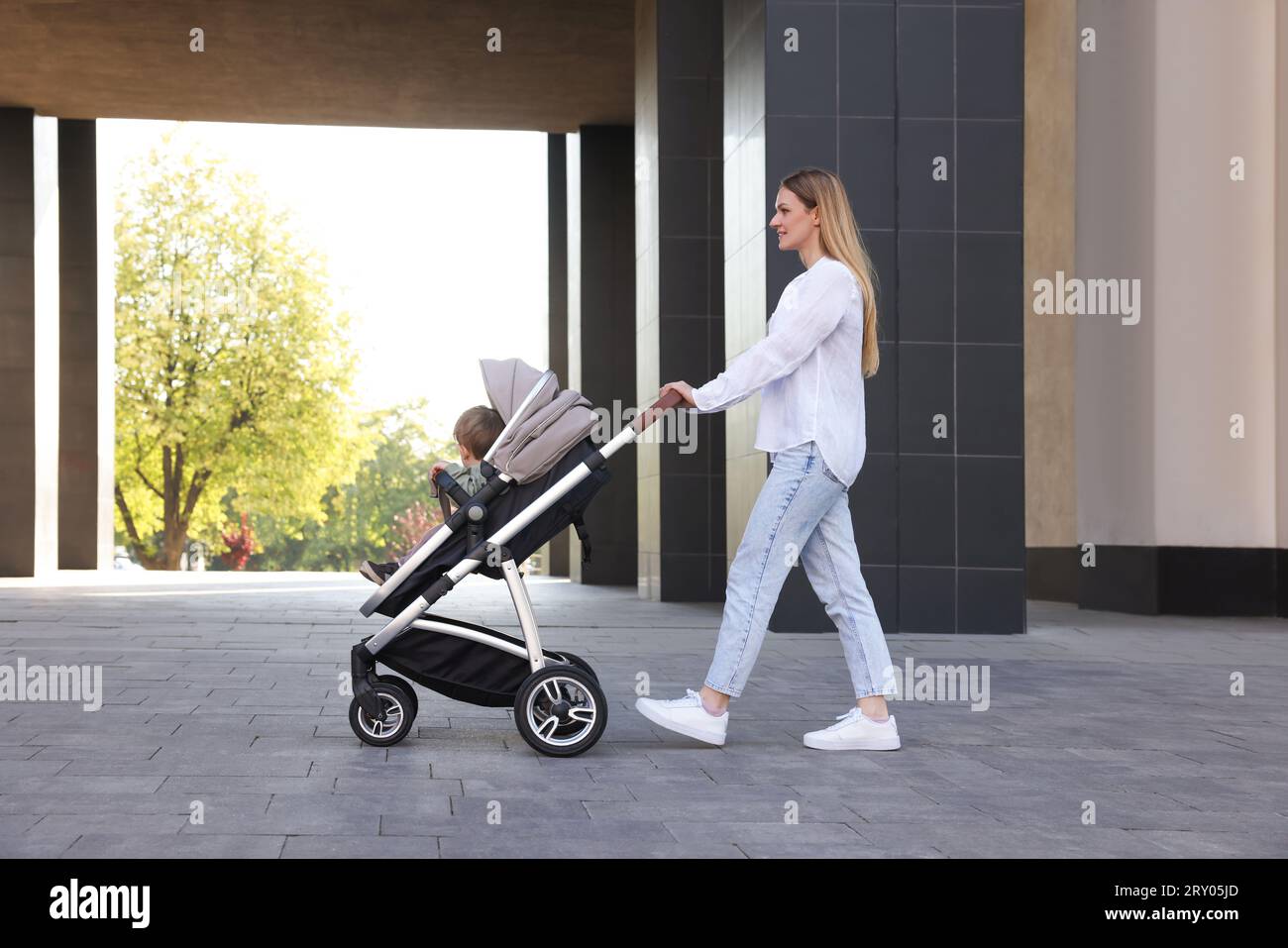 Happy nanny with cute little boy in stroller walking outdoors Stock ...