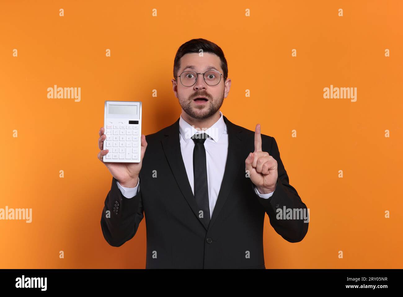 Emotional accountant with calculator on orange background Stock Photo ...