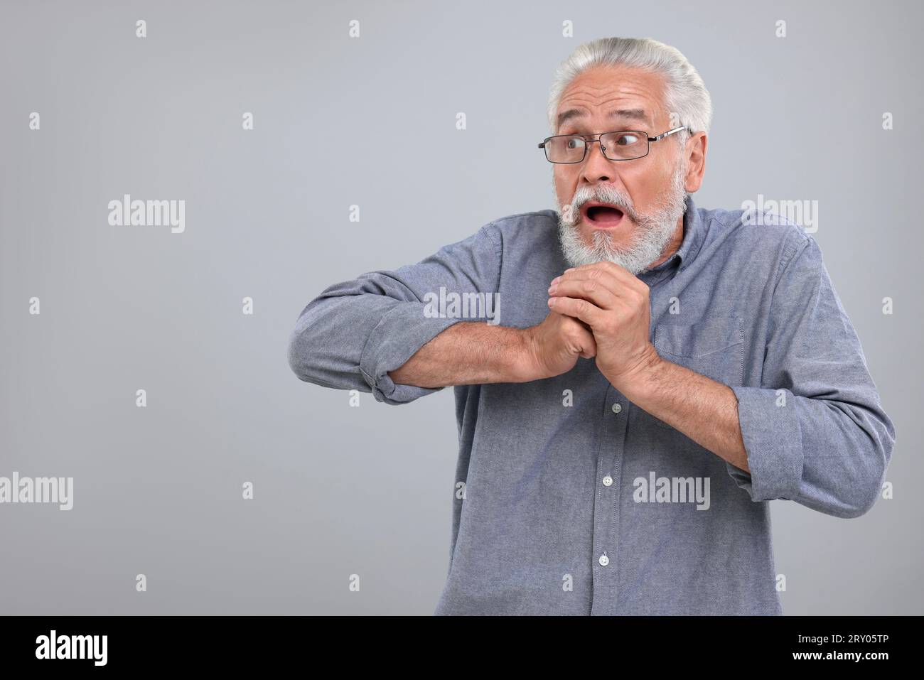 Portrait of embarrassed senior man on light grey background, space for ...