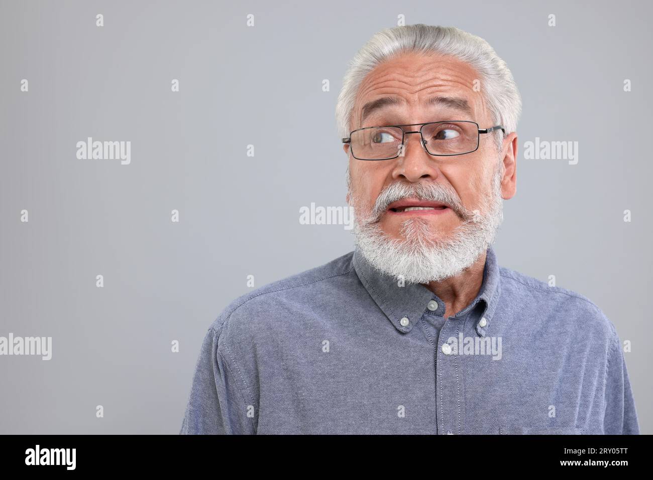 Portrait of embarrassed senior man on light grey background, space for ...