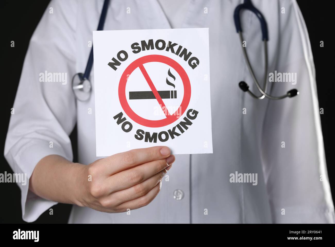 Doctor holding card with no smoking sign on black background, closeup ...