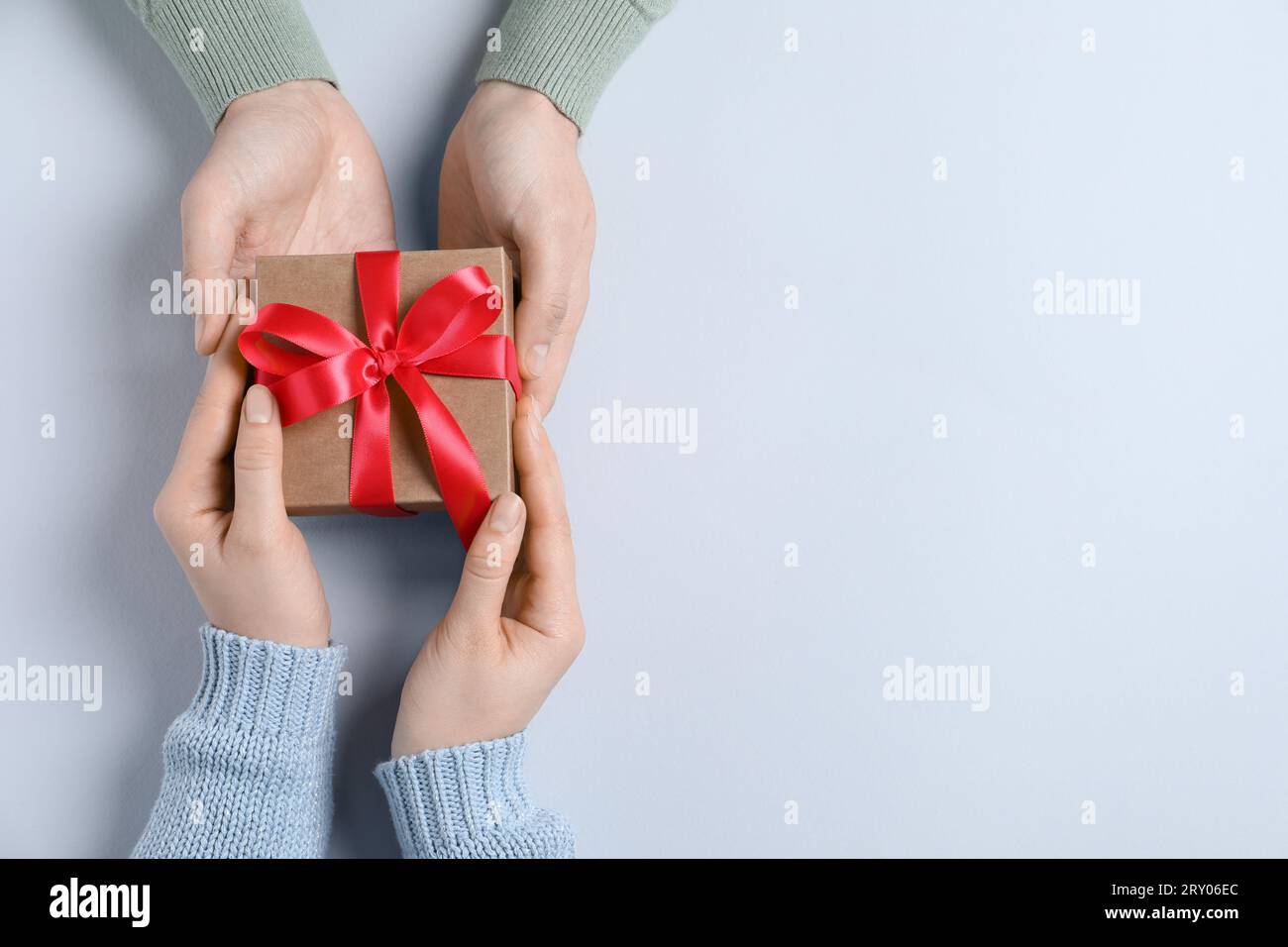 Man giving gift box to woman on light gray background, top view. Space ...
