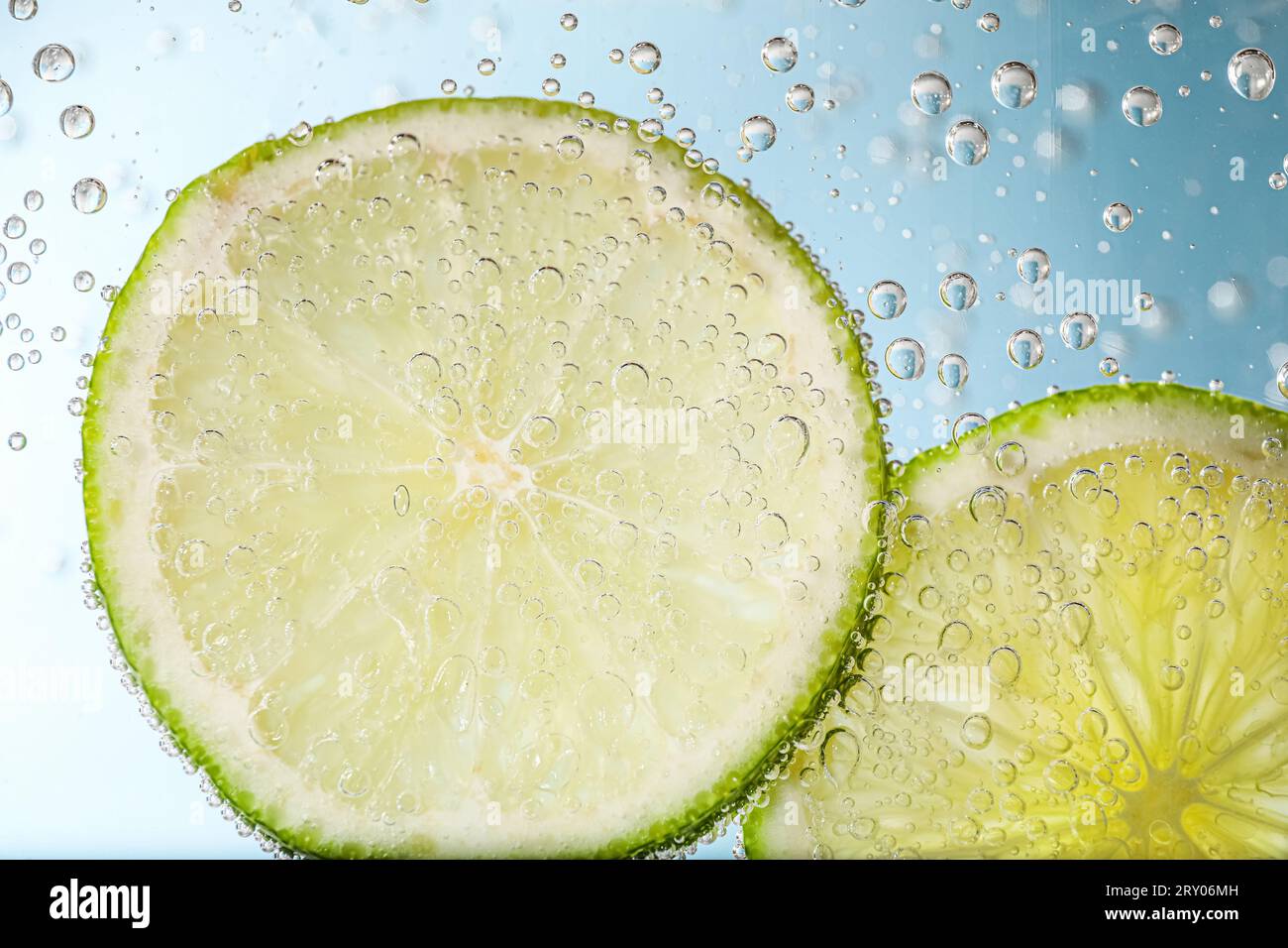 Juicy lime slices in soda water against light blue background, closeup Stock Photo - Alamy