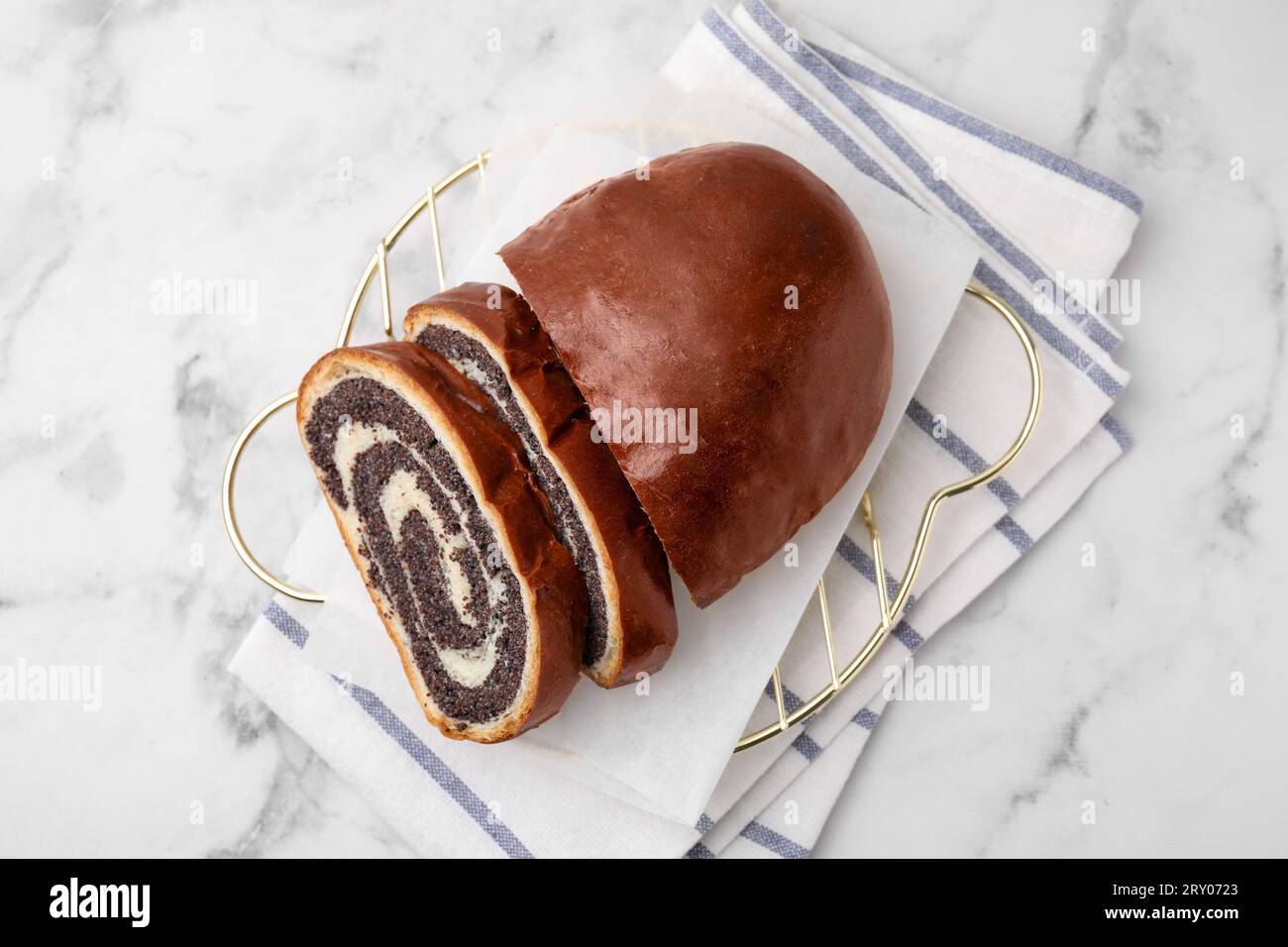 Slices of poppy seed roll on white marble table, top view. Tasty cake ...