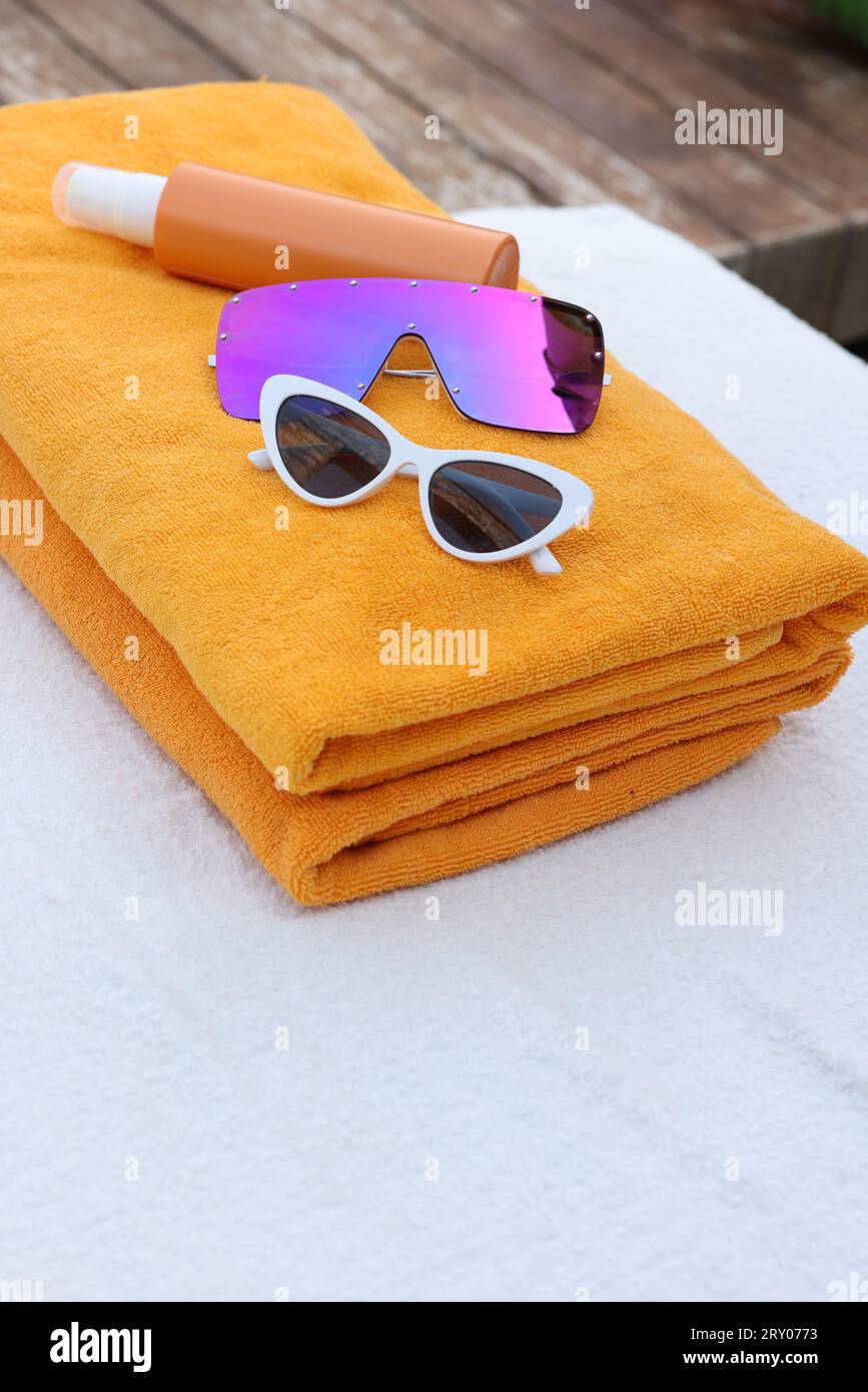 Beach towels, sunglasses and sunscreen on sunbed at resort Stock Photo ...
